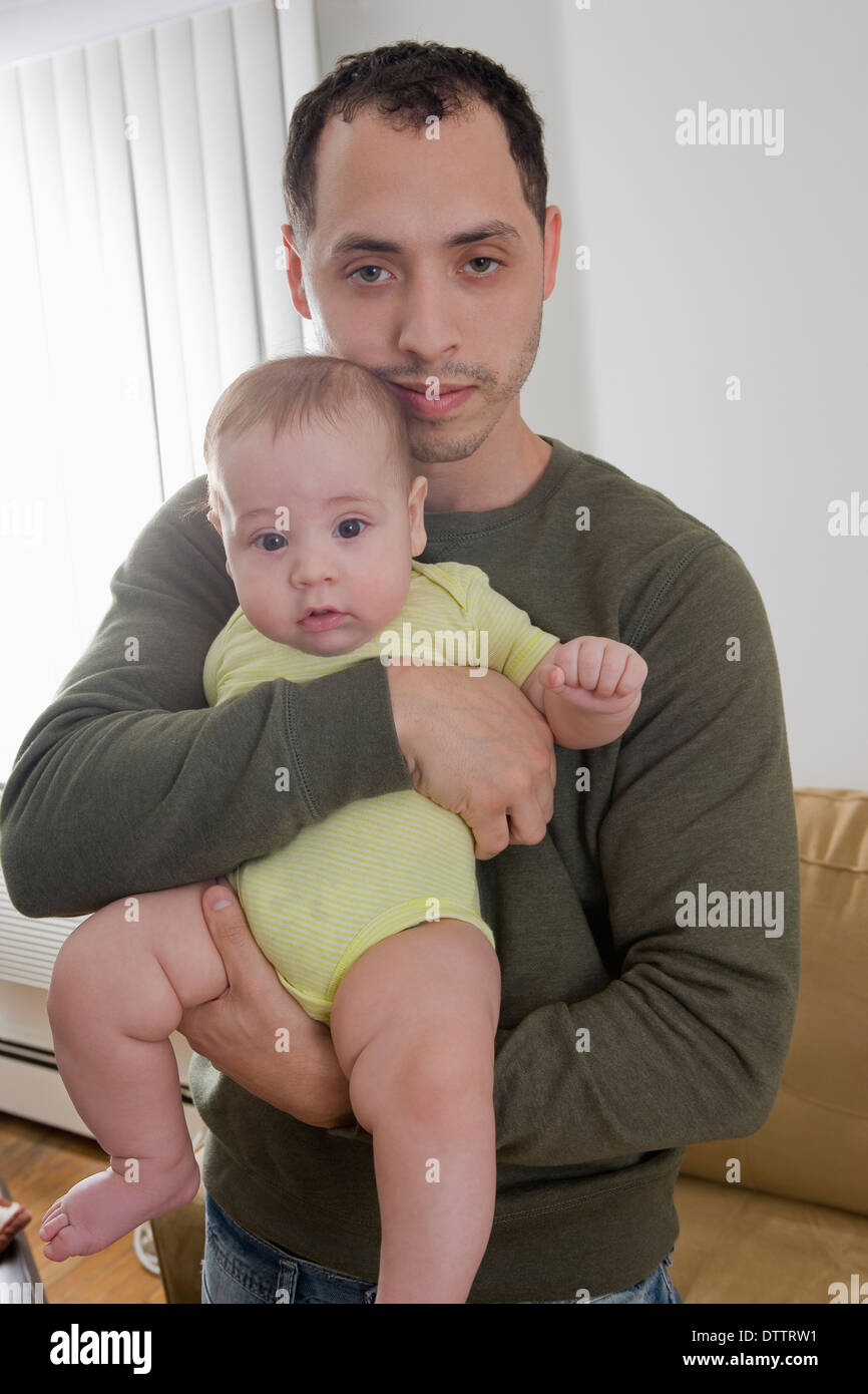 Father holding Hispanic baby in living room Stock Photo - Alamy