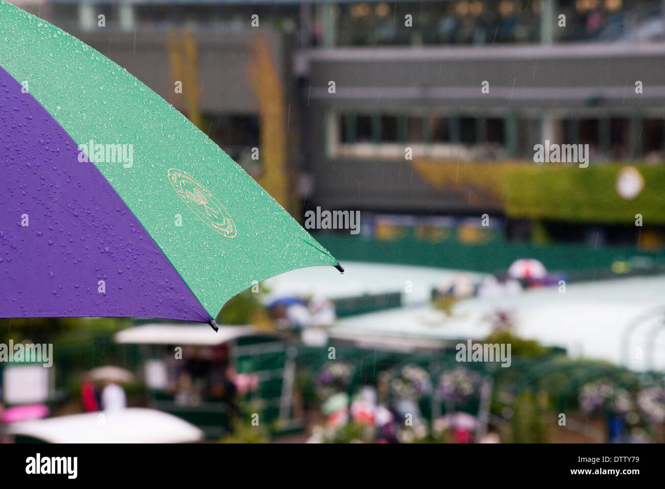 Wimbledon umbrella open in rain in front of out of focus wide shot of ...