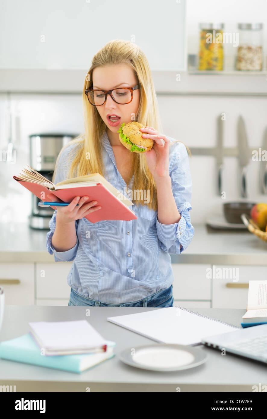 Young woman having snacks while studying in kitchen Stock Photo - Alamy