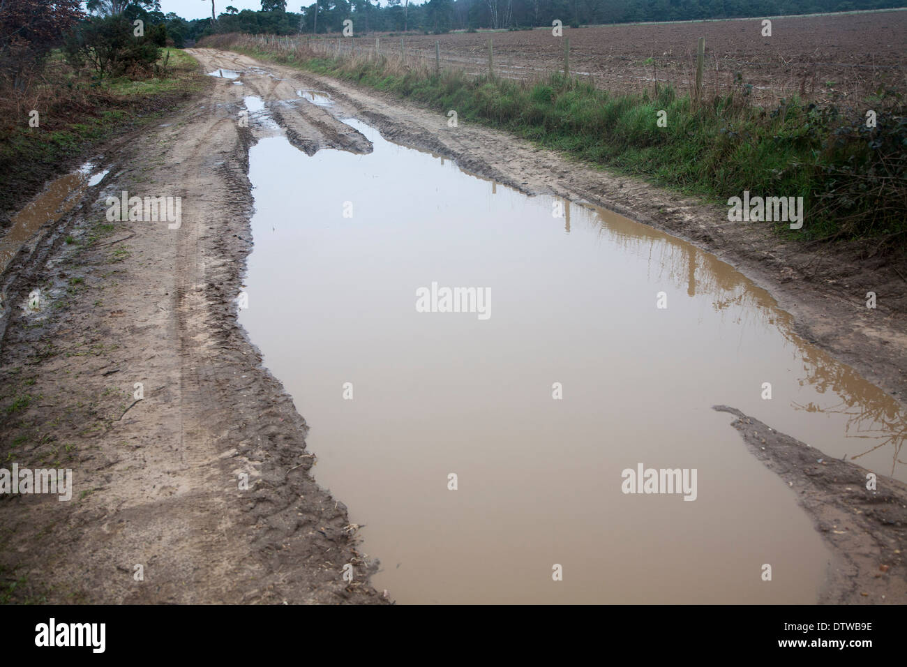 Waterlogged muddy unsurfaced road with large puddle after heavy rain in ...