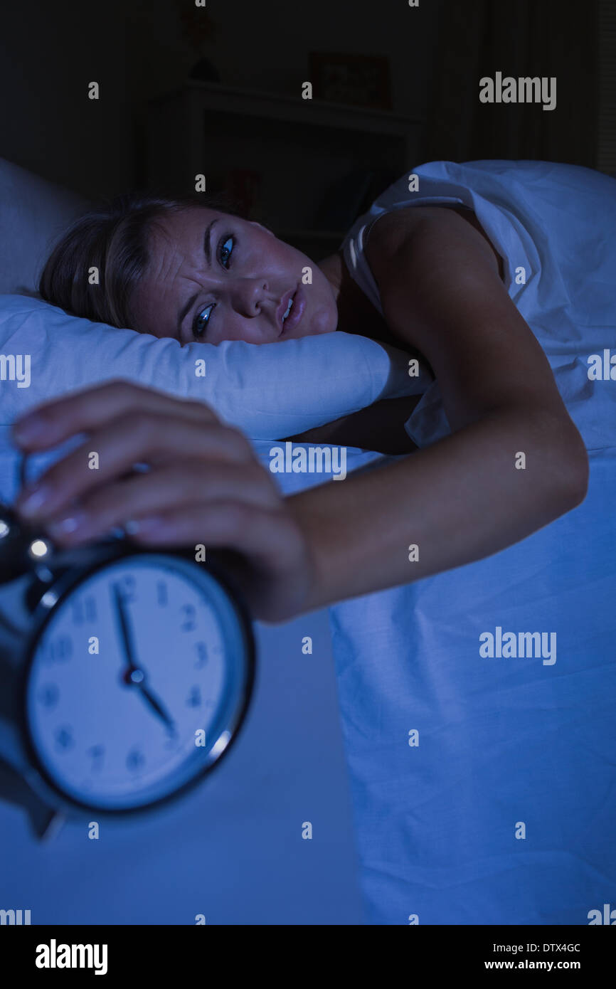 Blonde woman stopping her alarm clock Stock Photo - Alamy