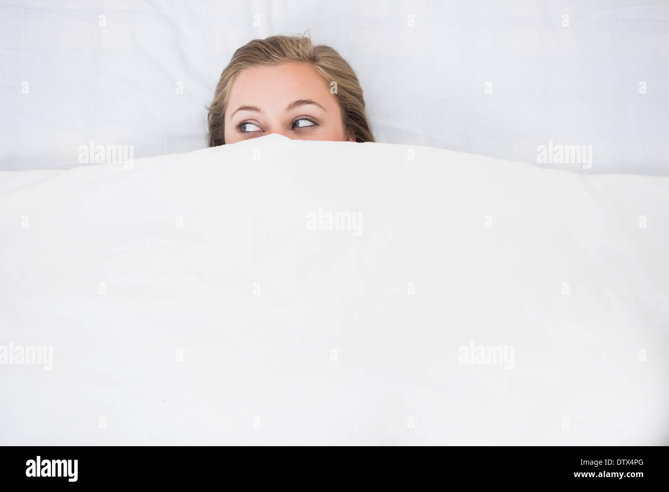 Blonde woman hiding under the duvet Stock Photo - Alamy