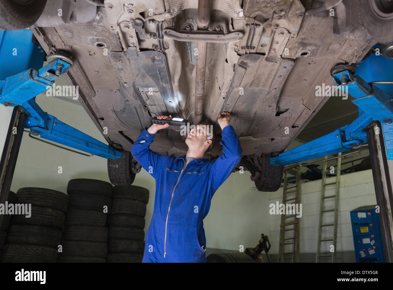 Mechanic inspecting car using flashlight Stock Photo - Alamy