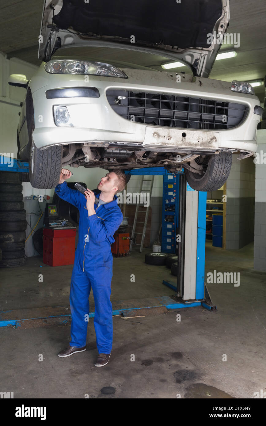Mechanic working under raised car in garage Stock Photo - Alamy