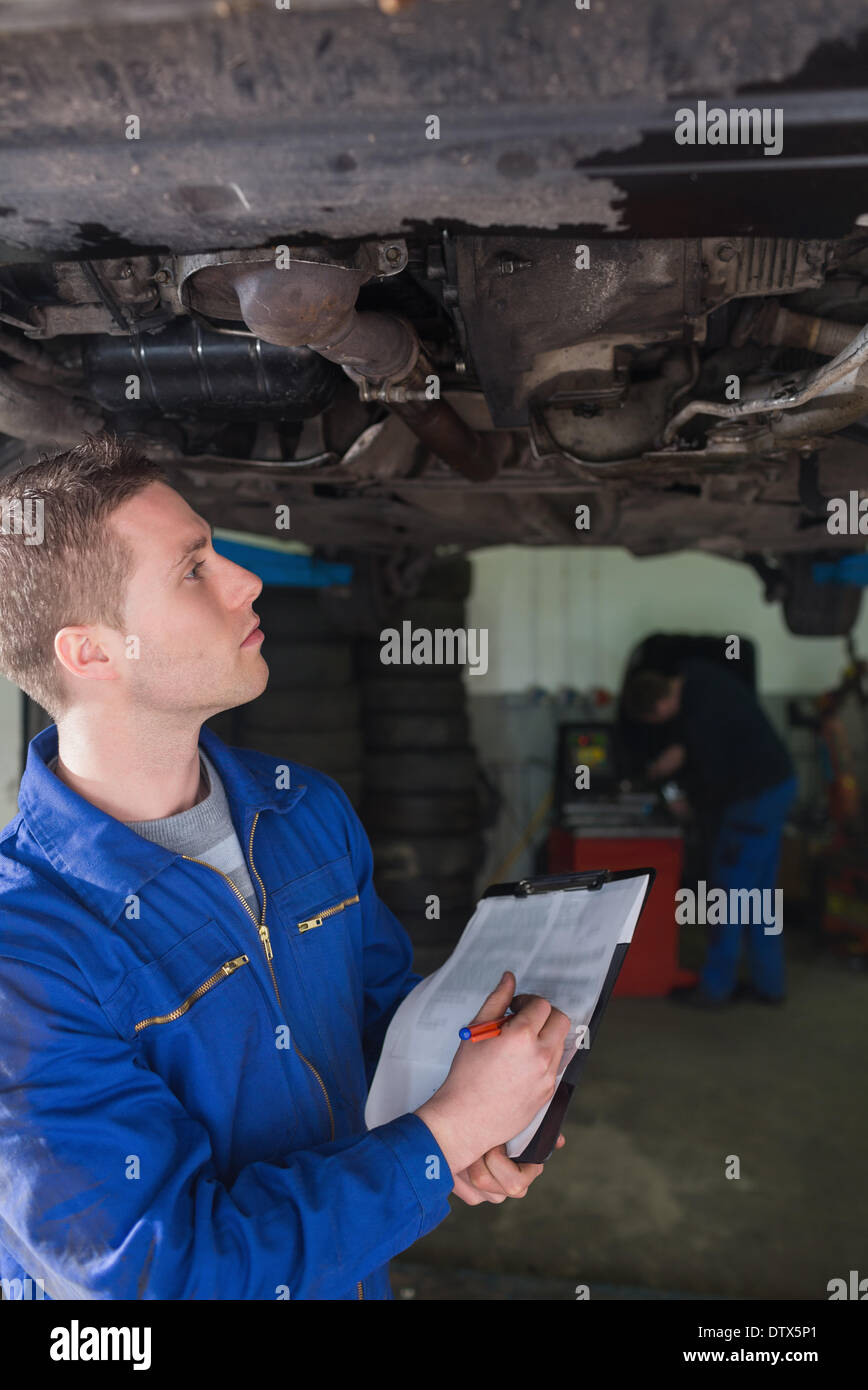 Mechanic with clipboard examining car Stock Photo - Alamy