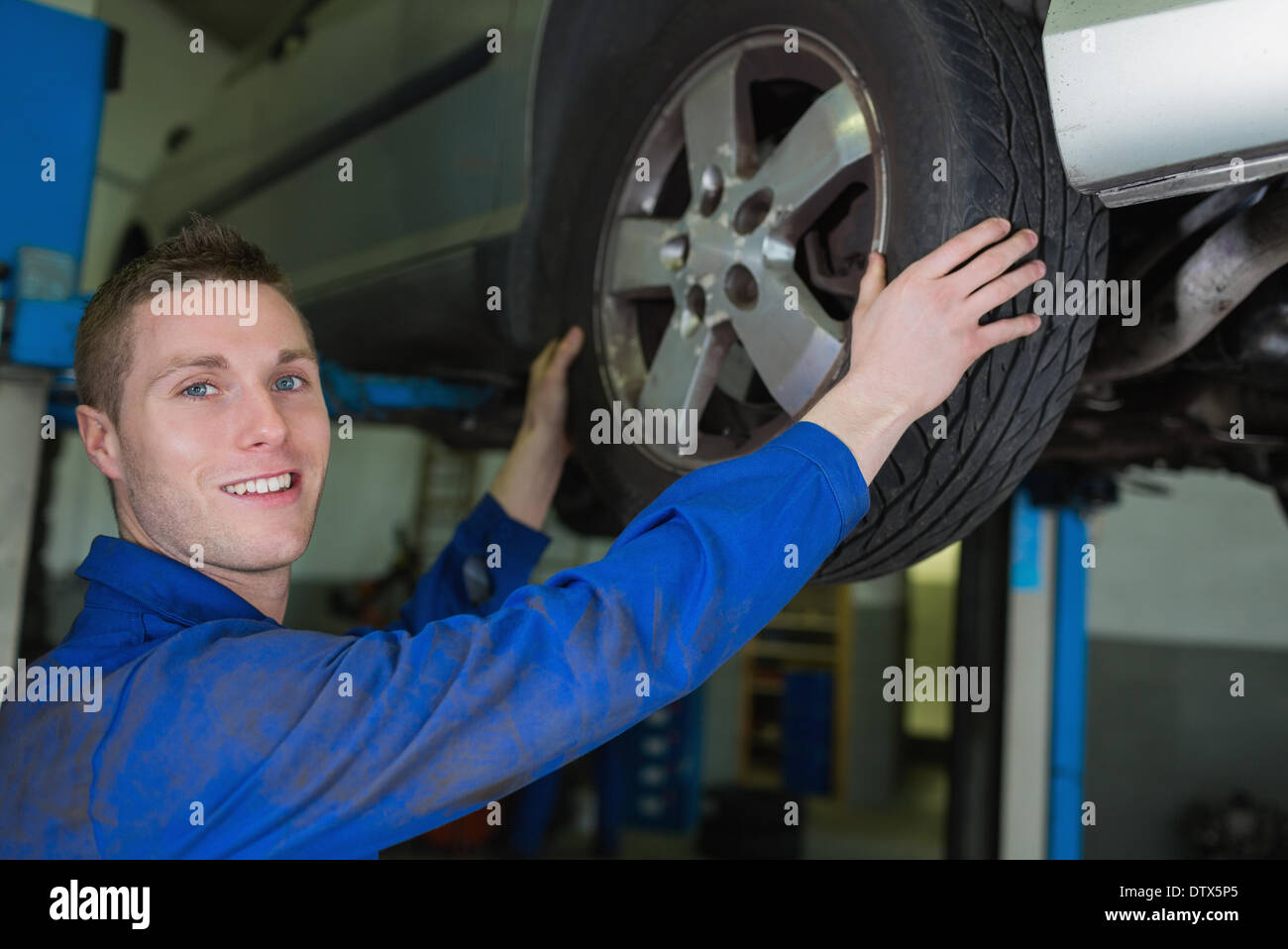 Male mechanic working on wheel of car Stock Photo - Alamy