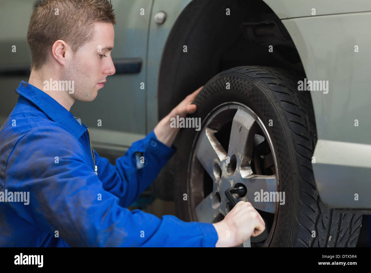 Male mechanic changing car wheel Stock Photo - Alamy