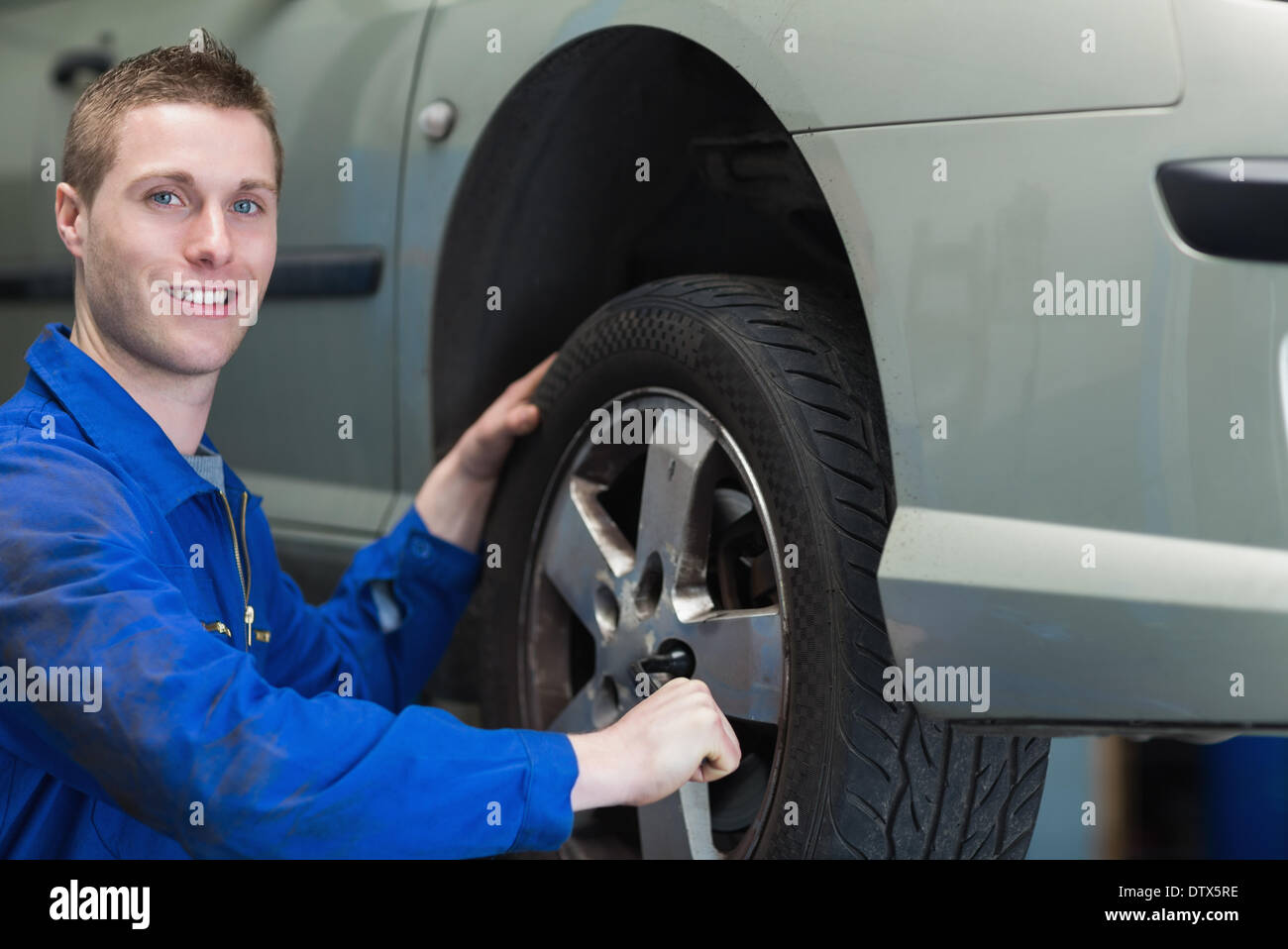 Happy mechanic changing car tyre Stock Photo - Alamy