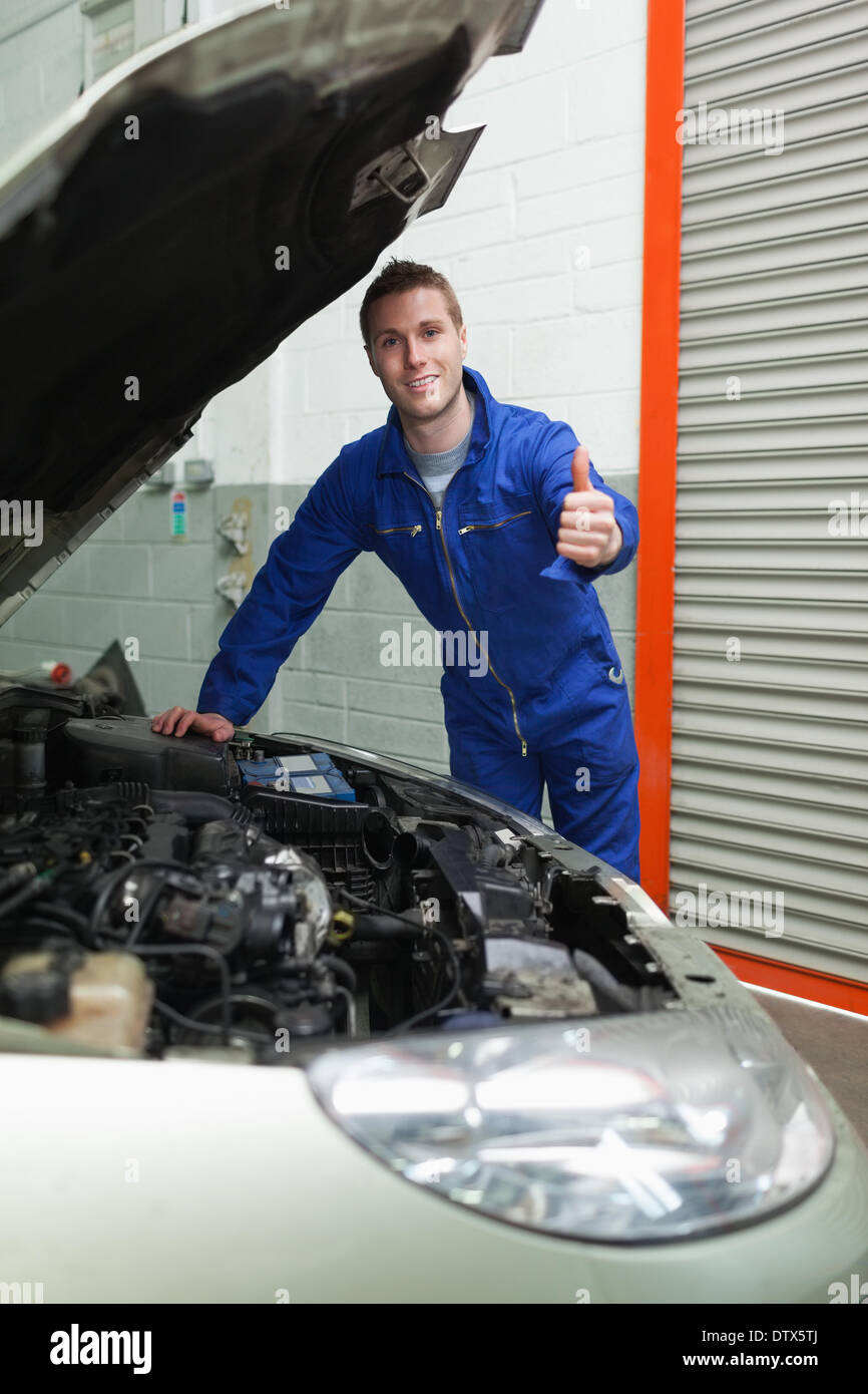 Auto mechanic by car gesturing thumbs up Stock Photo - Alamy