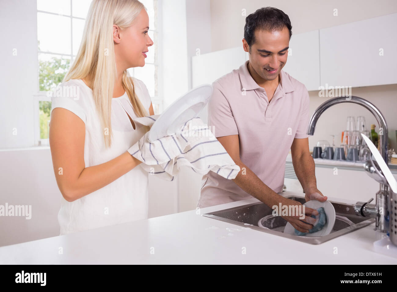 Happy couple washing dishes together Stock Photo - Alamy