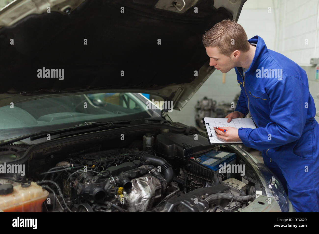 Mechanic writing on clipboard Stock Photo - Alamy