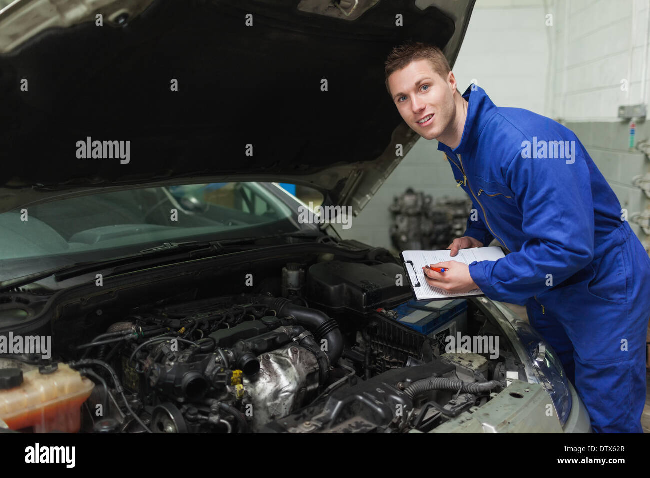 Mechanic with clipboard by car Stock Photo - Alamy