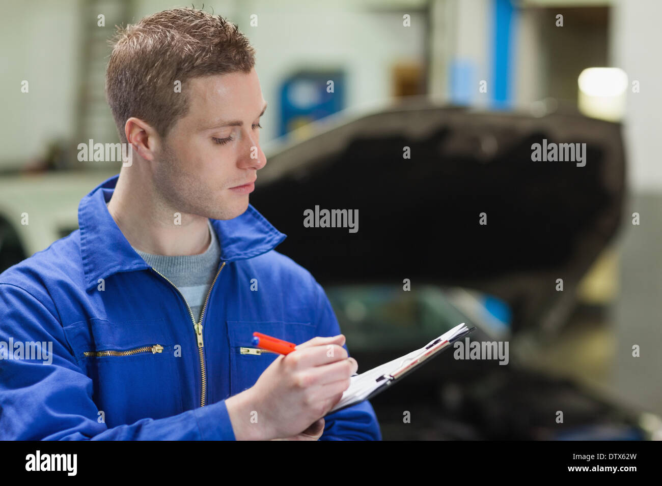 Mechanic writing on clipboard Stock Photo - Alamy
