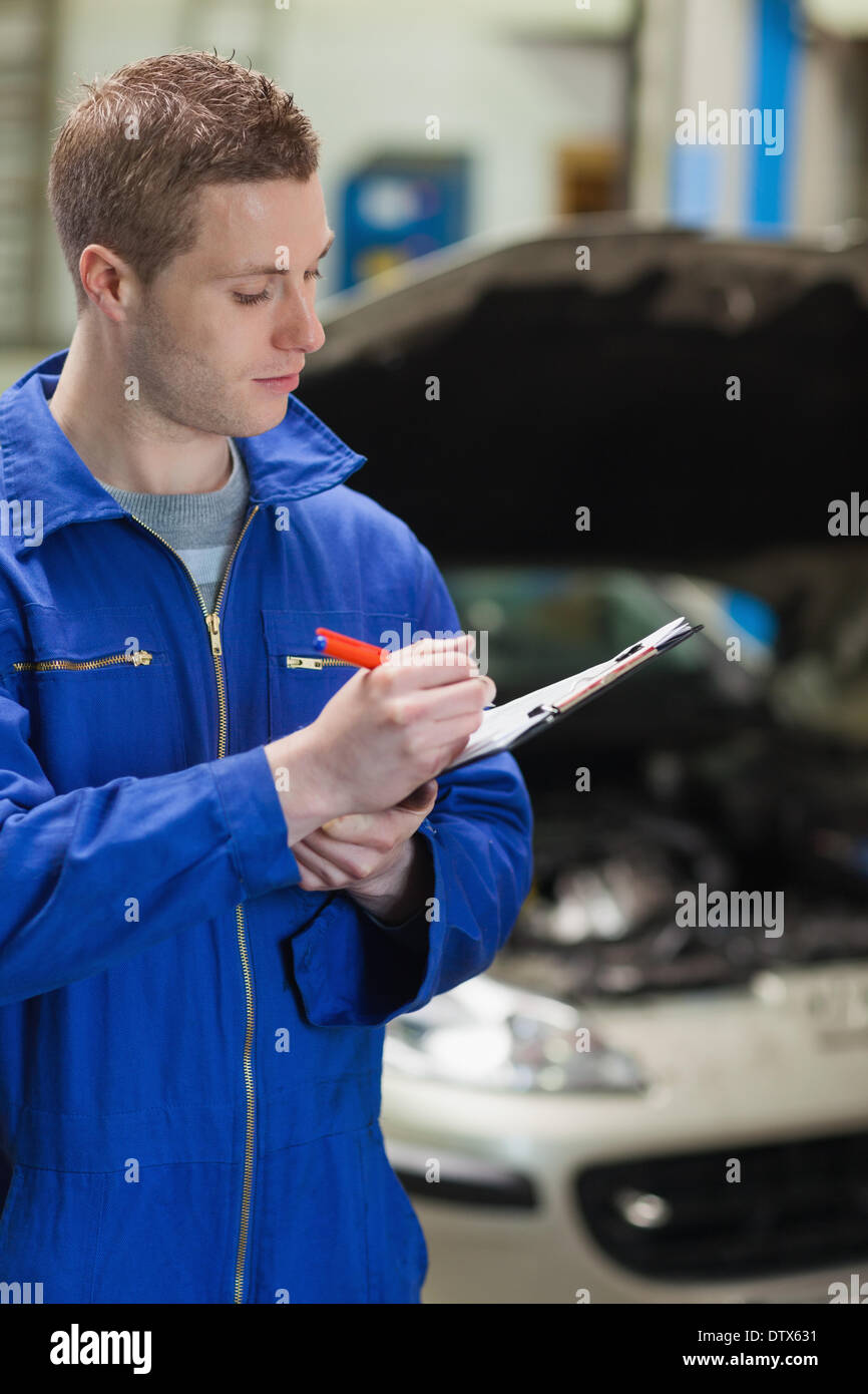 Auto mechanic writing on clipboard Stock Photo - Alamy