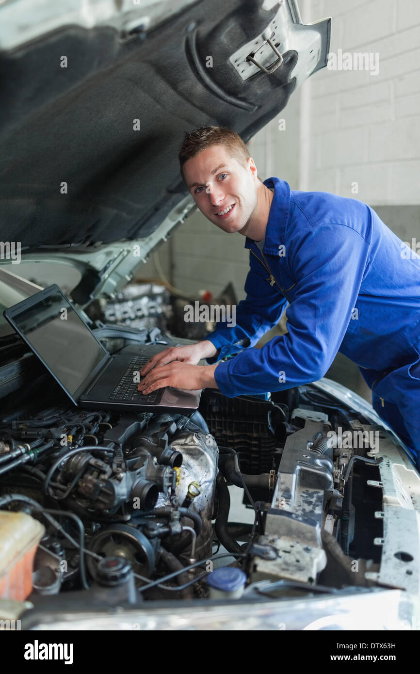 Mechanic using laptop on car engine Stock Photo - Alamy