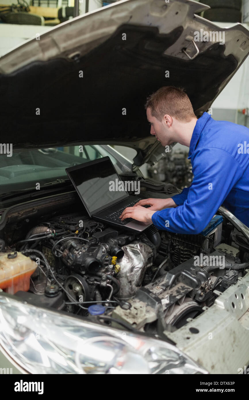 Mechanic using laptop on car engine Stock Photo - Alamy