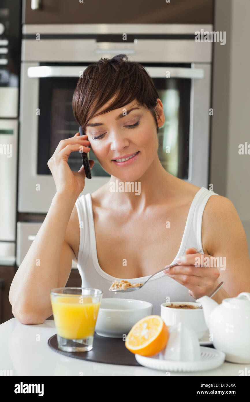 Woman eating breakfast and talking on phone Stock Photo - Alamy