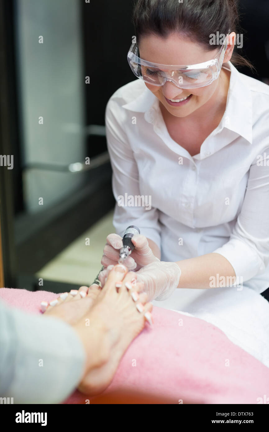 Nail technician removing callus at feet Stock Photo - Alamy
