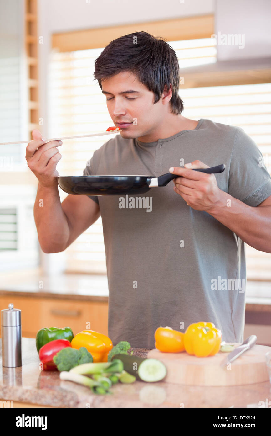 Young man smelling food in the kitchen Stock Photo - Alamy