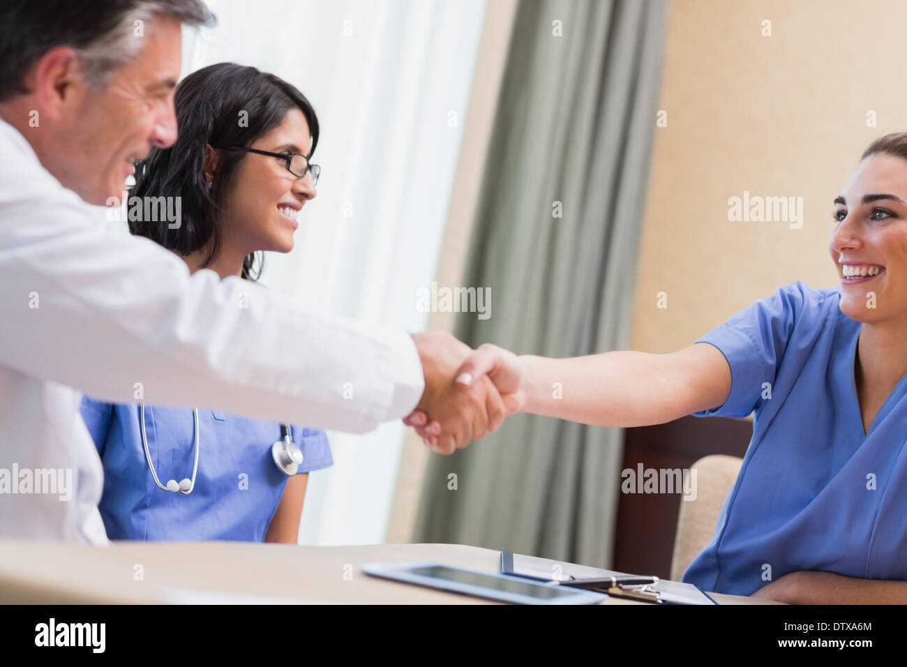Nurse and doctor shaking hands Stock Photo - Alamy