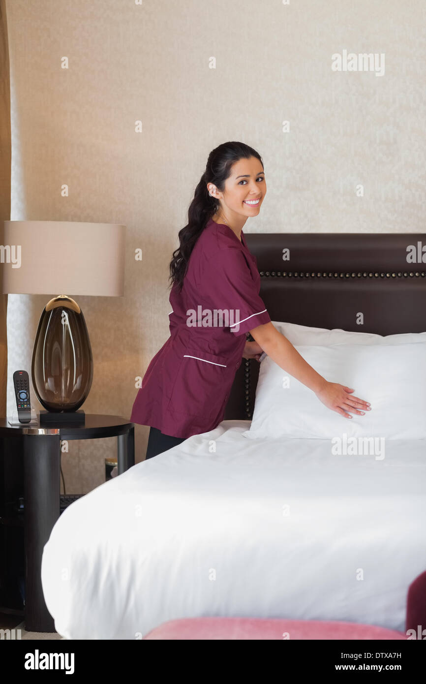 Happy hotel maid fixing pillows Stock Photo - Alamy