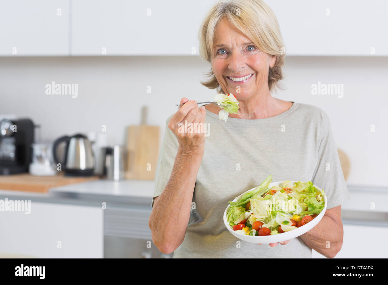 Smiling woman eating salad Stock Photo - Alamy