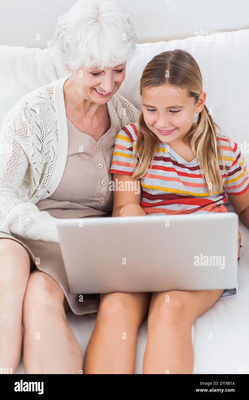 Smiling girl using laptop with granny Stock Photo - Alamy