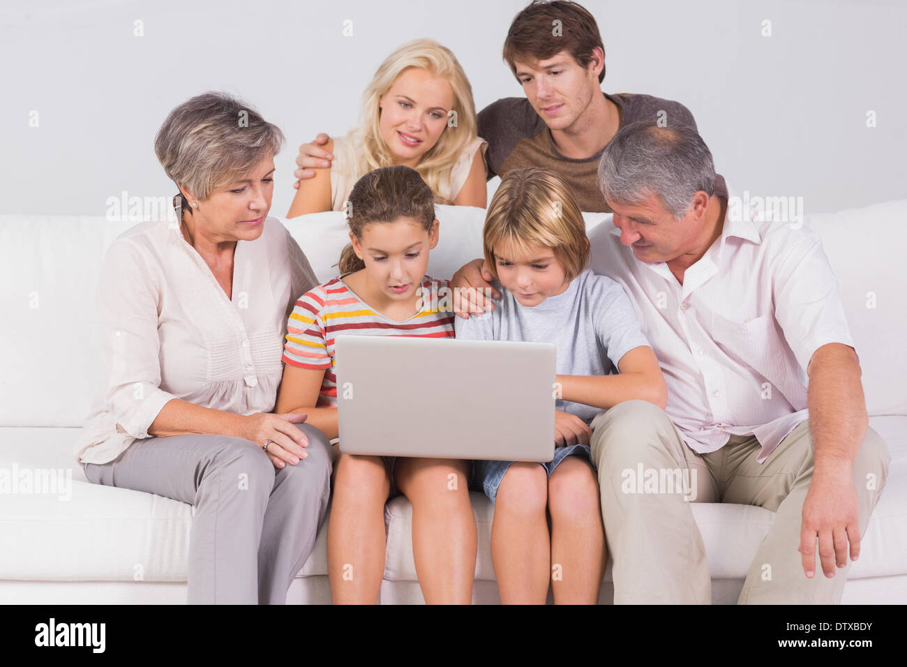 Family looking at laptop on couch Stock Photo - Alamy