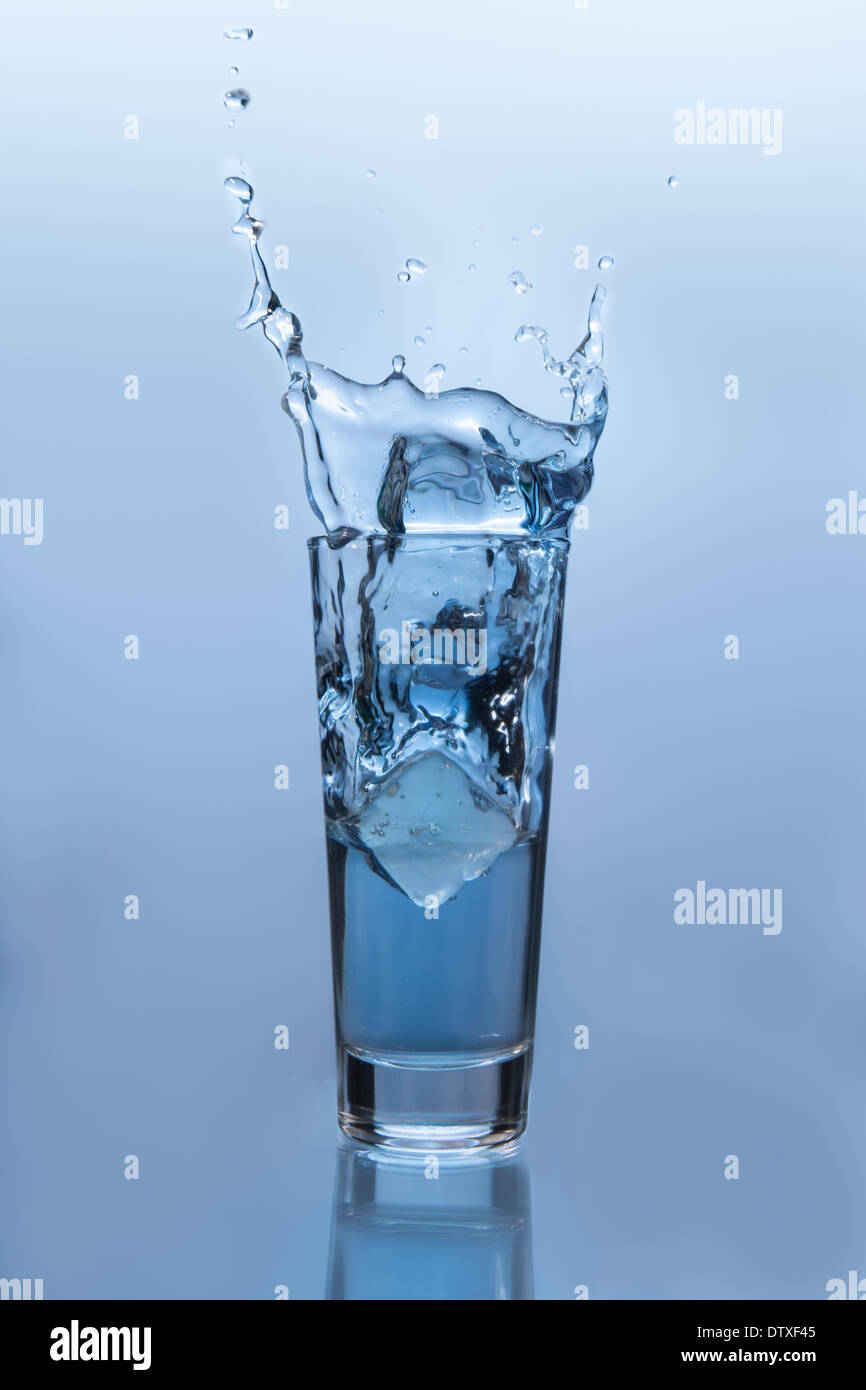 Ice cube falling into glass of water Stock Photo - Alamy