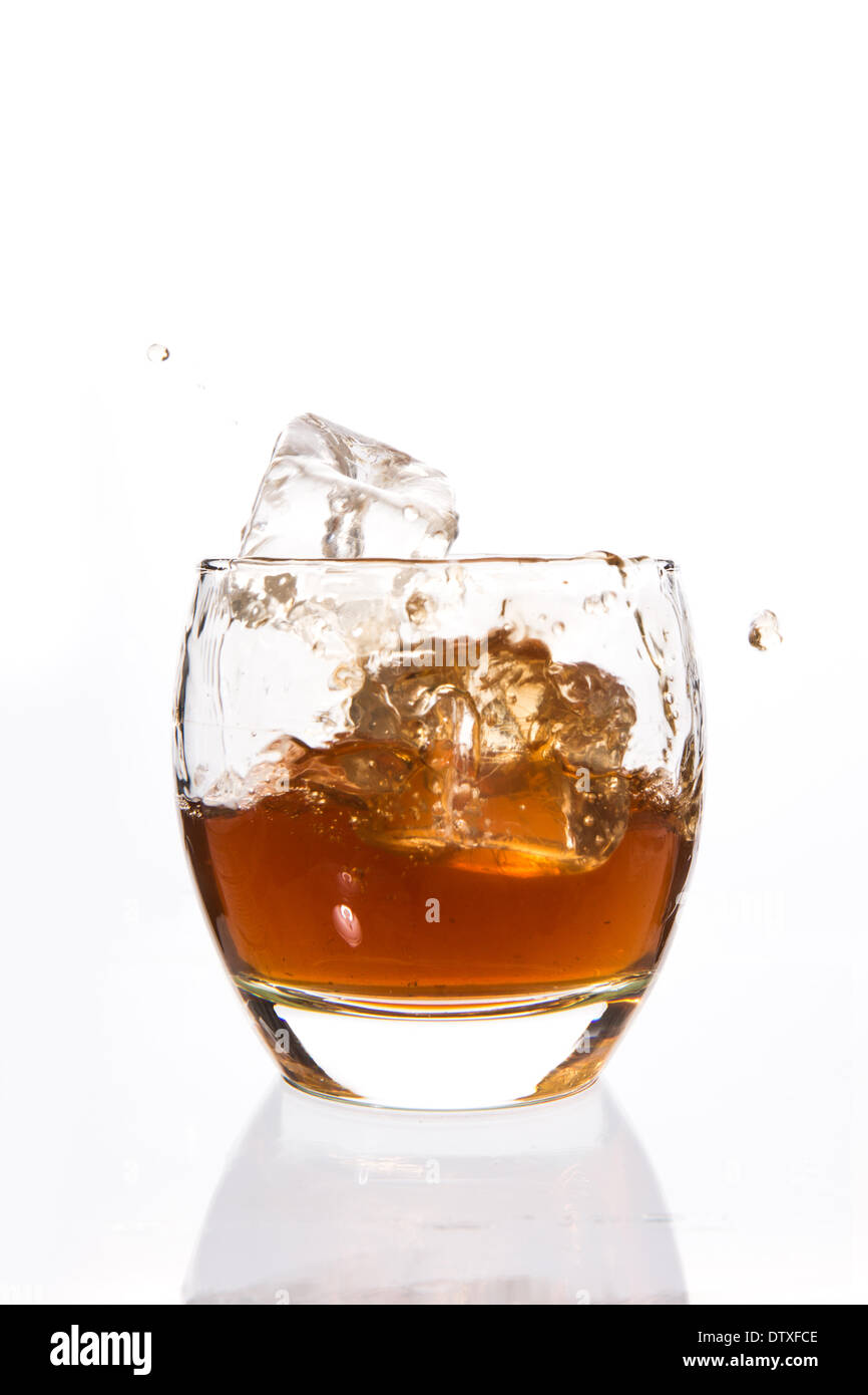 Ice cubes falling in a tumbler of whiskey Stock Photo - Alamy