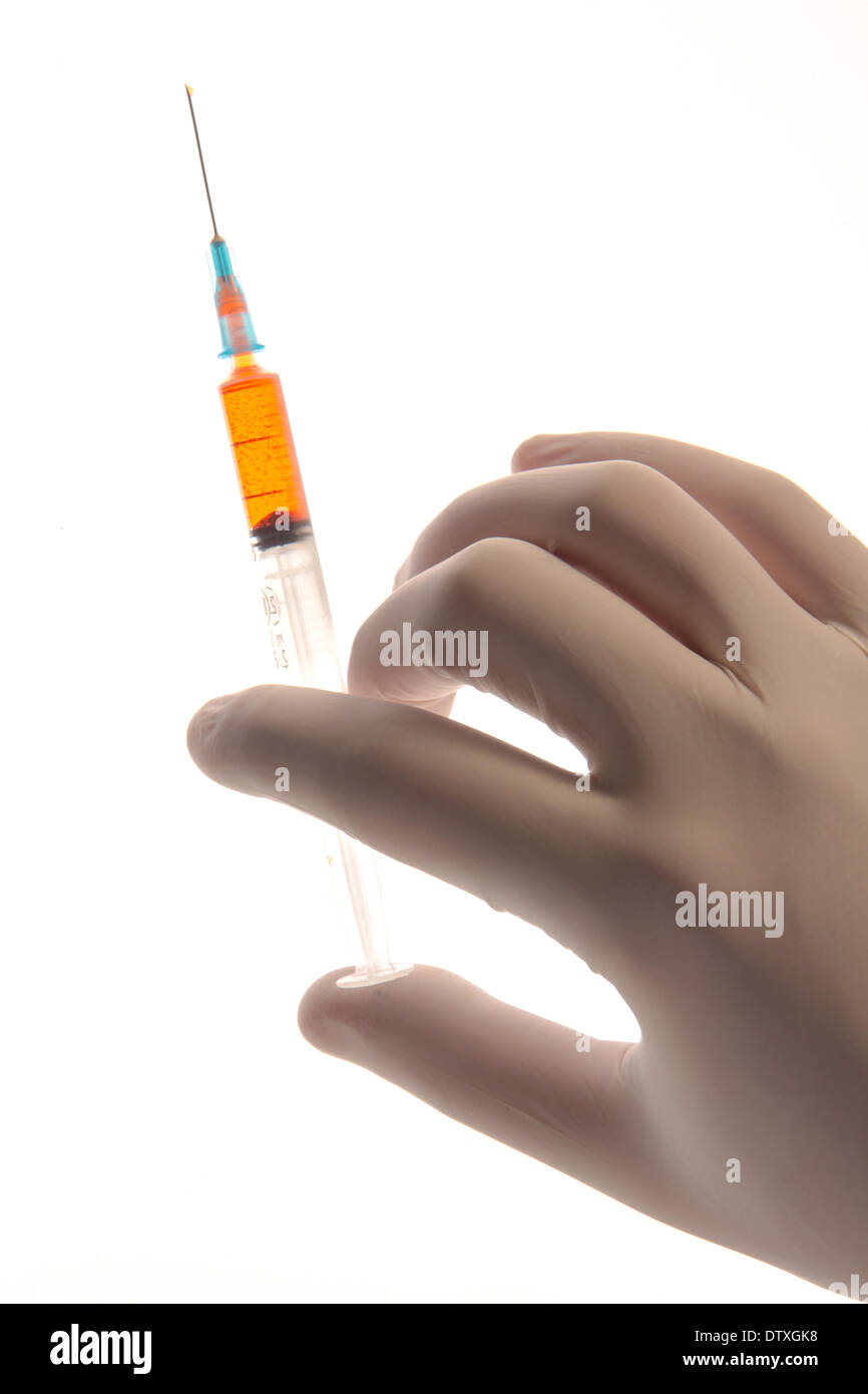 Gloved hand holding a syringe Stock Photo - Alamy