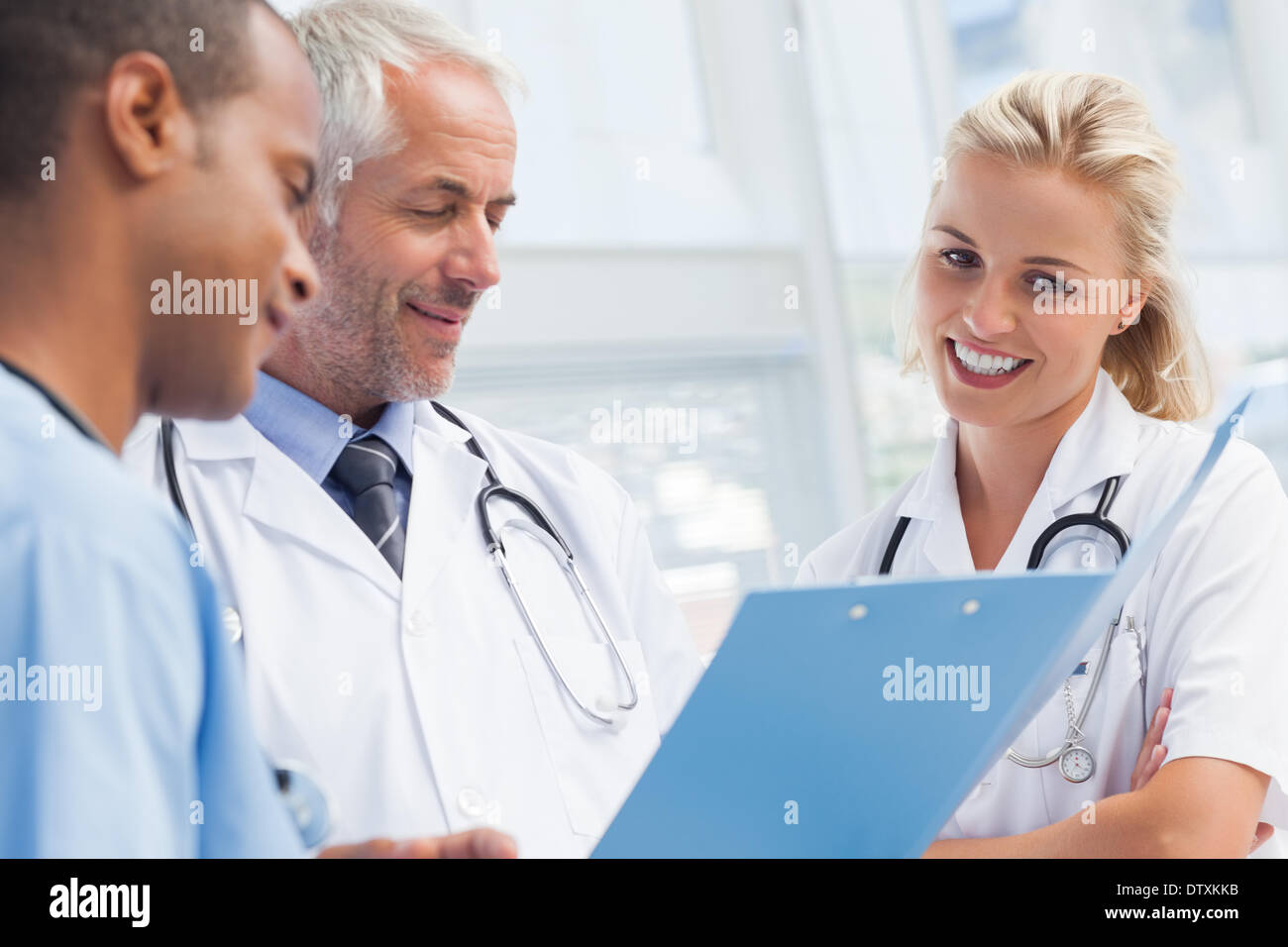 Three doctors examining a file Stock Photo - Alamy