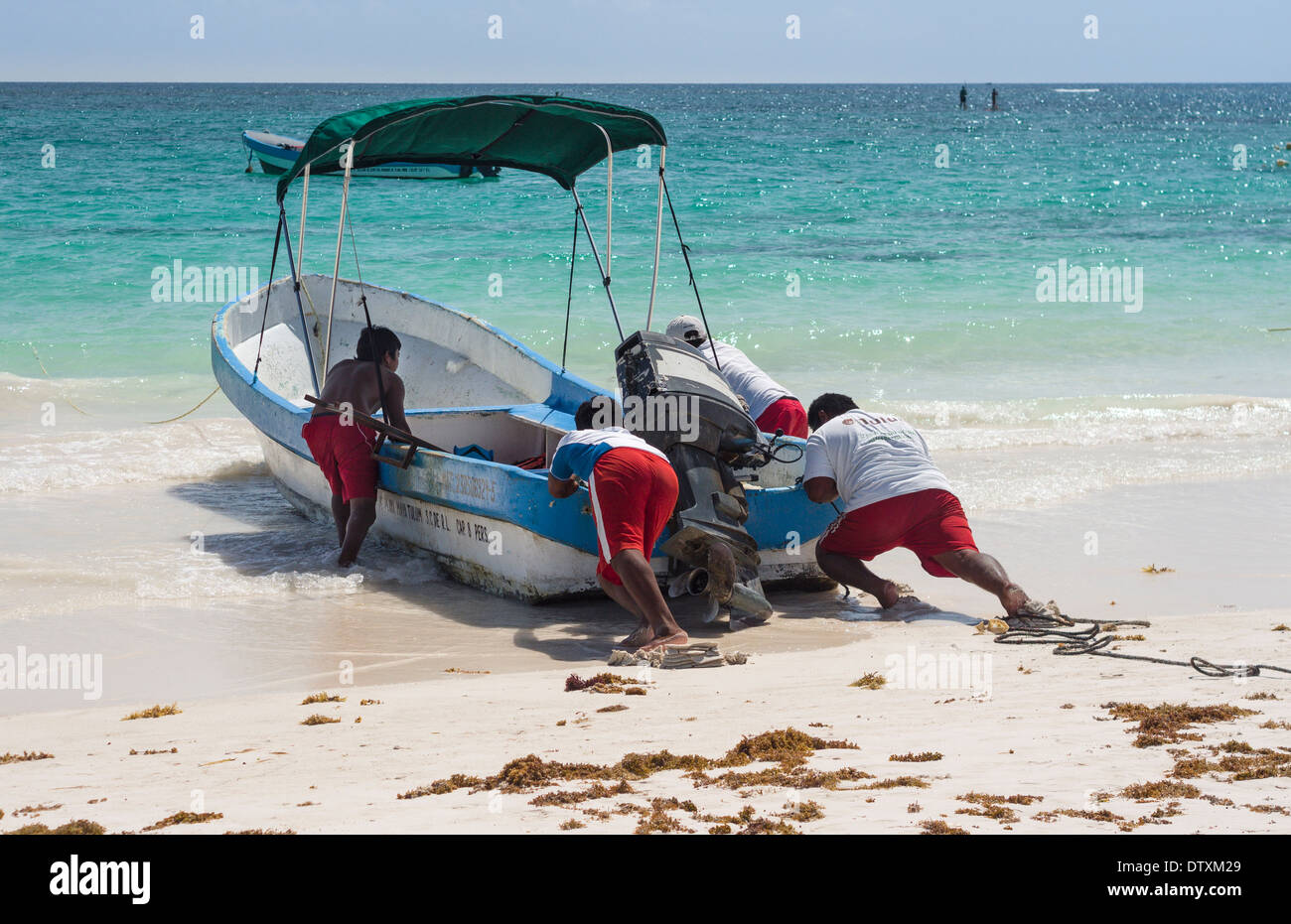 The big push off the beach. A crew of a fishing boat dig into the sand ...