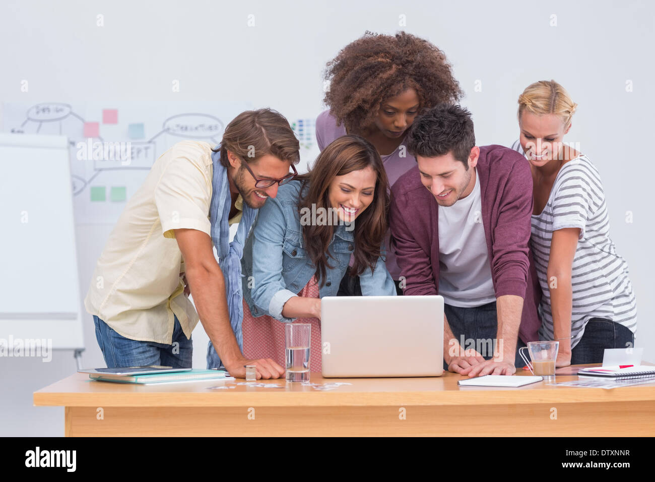 Creative team looking at laptop Stock Photo - Alamy