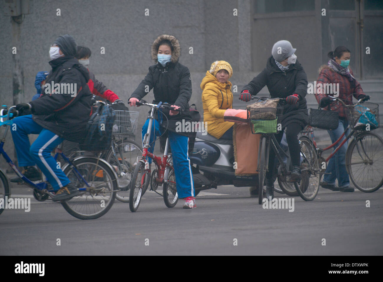 People wearing masks ride bicycles along a street on a hazy morning in ...