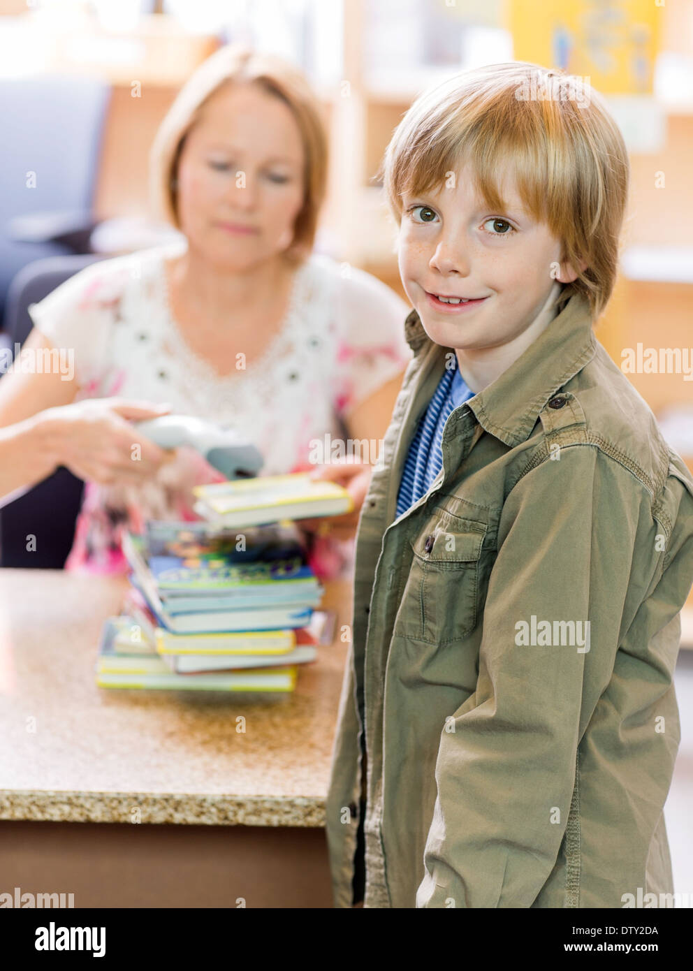 Boy With Librarian Scanning Books At Library Counter Stock Photo - Alamy