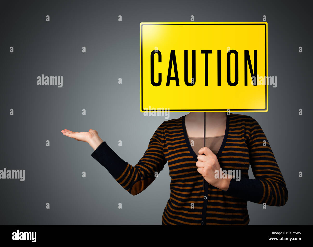 Young woman holding a caution sign Stock Photo - Alamy