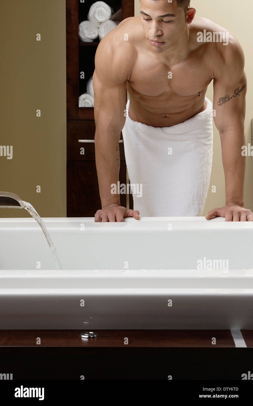 Mixed race man running bath Stock Photo - Alamy