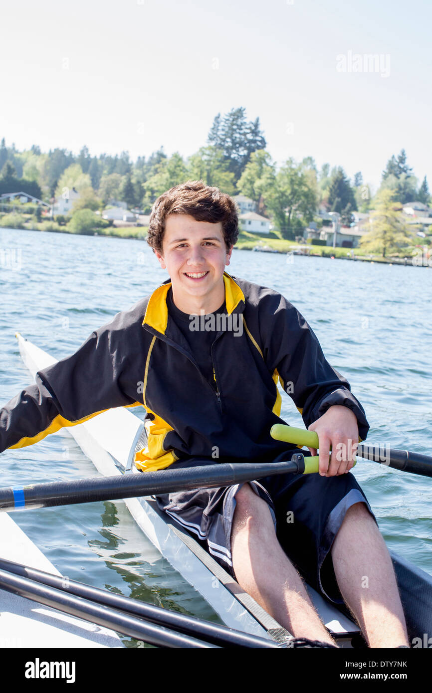 Mixed race teenage boy rowing scull on lake Stock Photo - Alamy