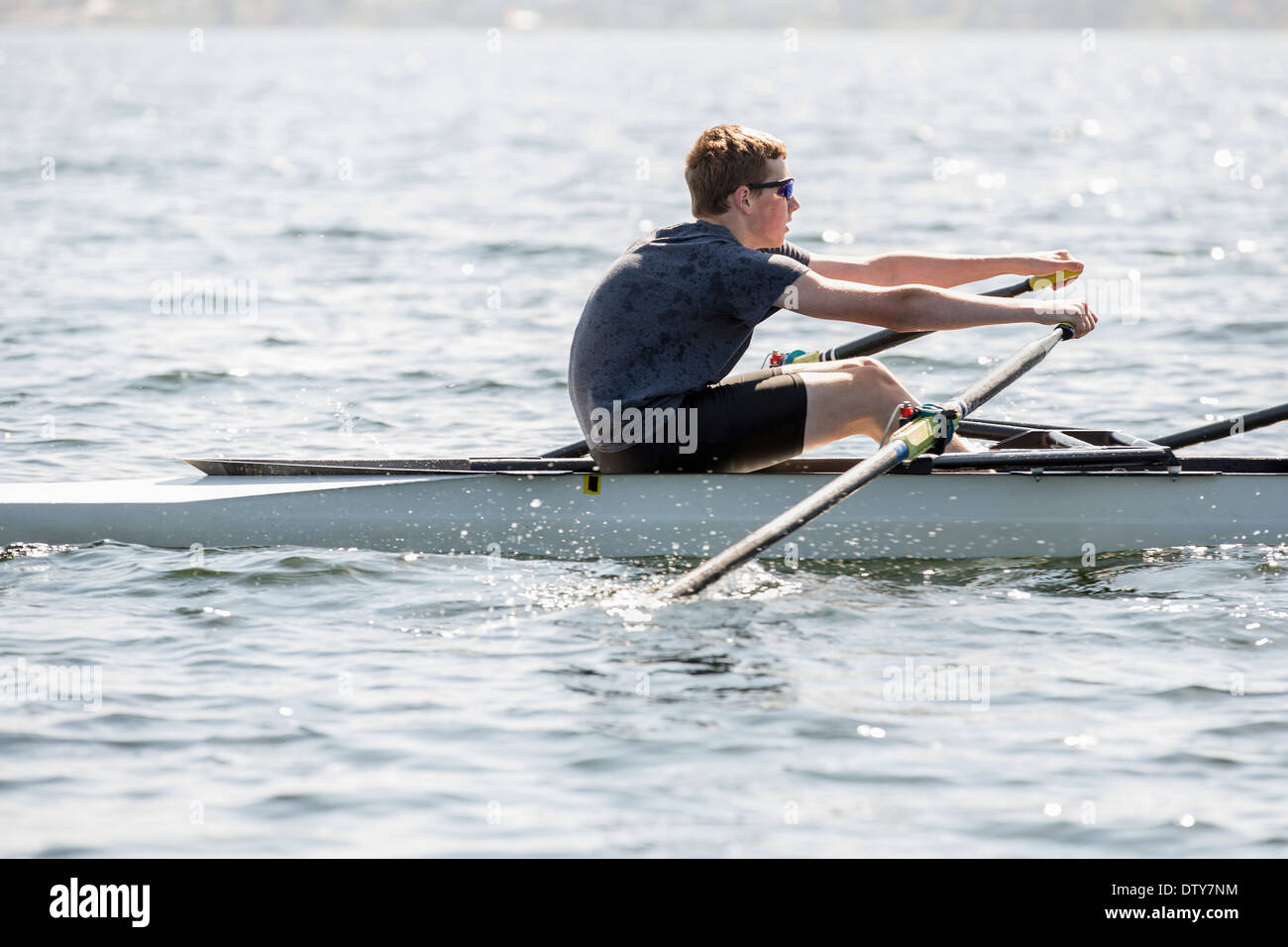 Caucasian teenage boy rowing on river Stock Photo - Alamy