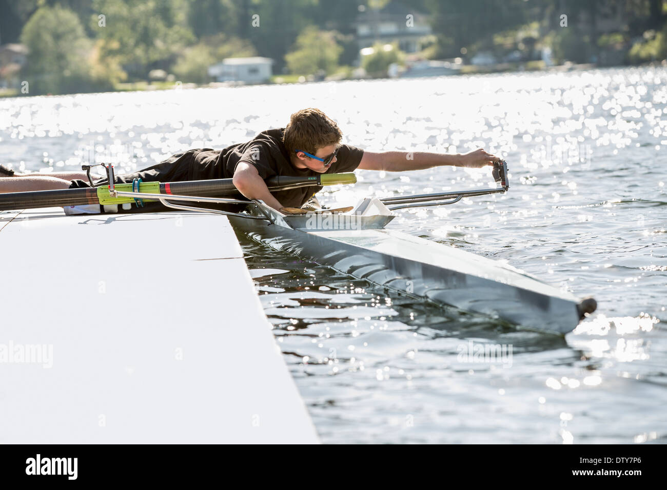 Teenage boy preparing scull from dock over lake Stock Photo - Alamy