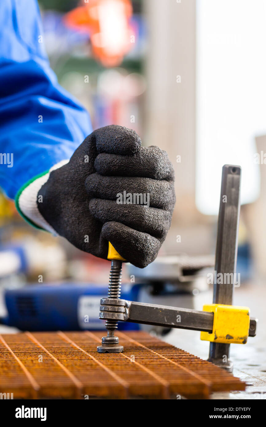 Craftsman clamping metal with workbench clamp in workshop Stock Photo ...