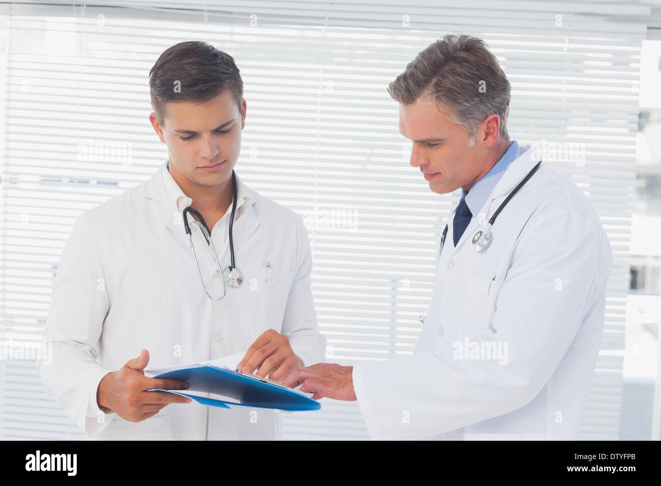 Doctors reading a folder Stock Photo - Alamy