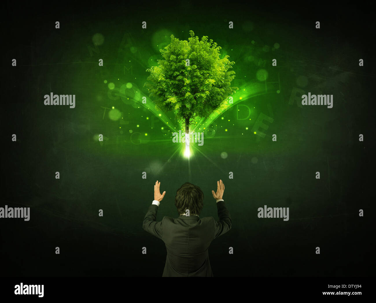 Businessman gesturing in front of a glowing tree Stock Photo - Alamy