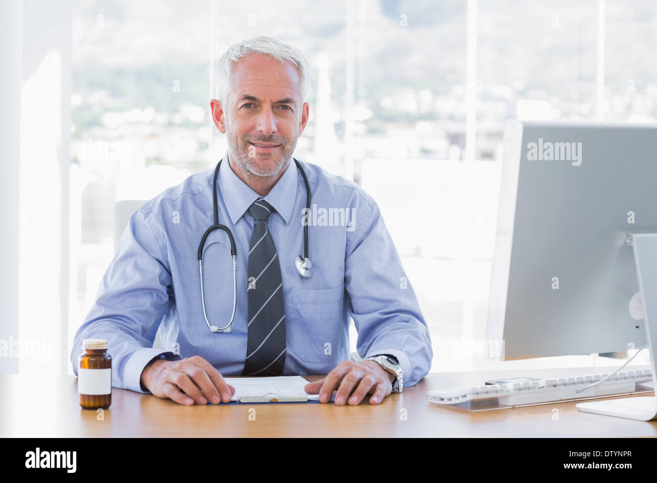Attractive doctor sitting at his desk Stock Photo - Alamy