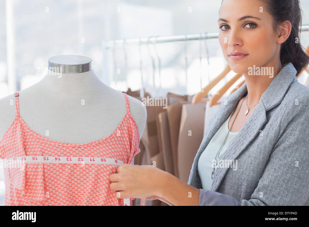 Pretty fashion designer measuring dress Stock Photo - Alamy