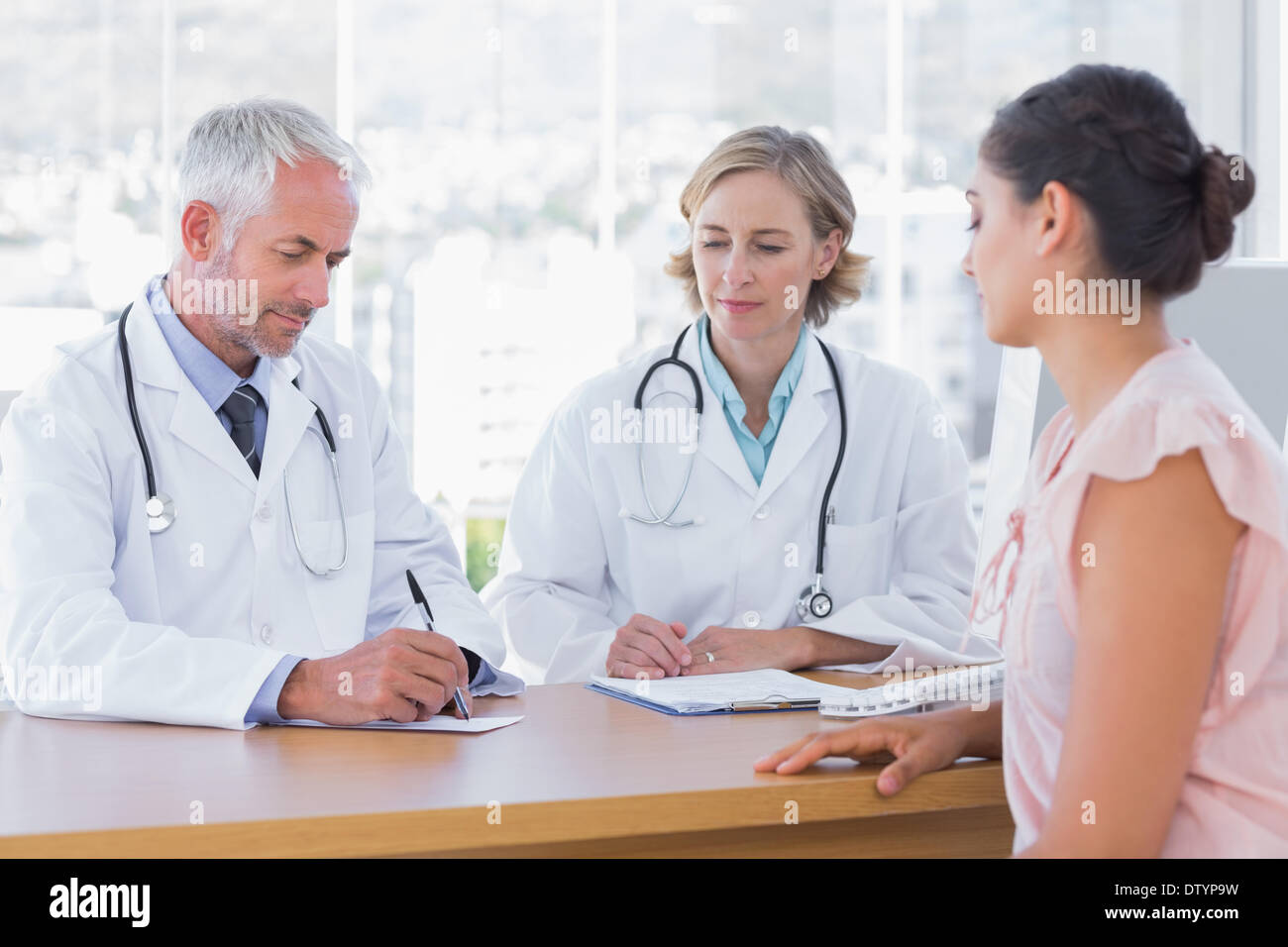 Two doctors with a female patient Stock Photo - Alamy