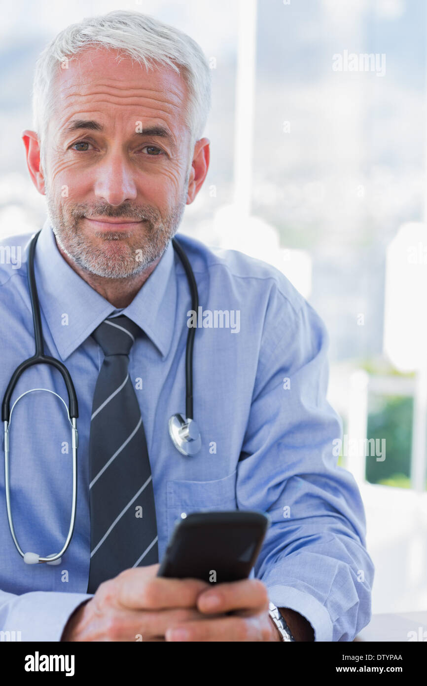 Attractive doctor using his smartphone Stock Photo - Alamy