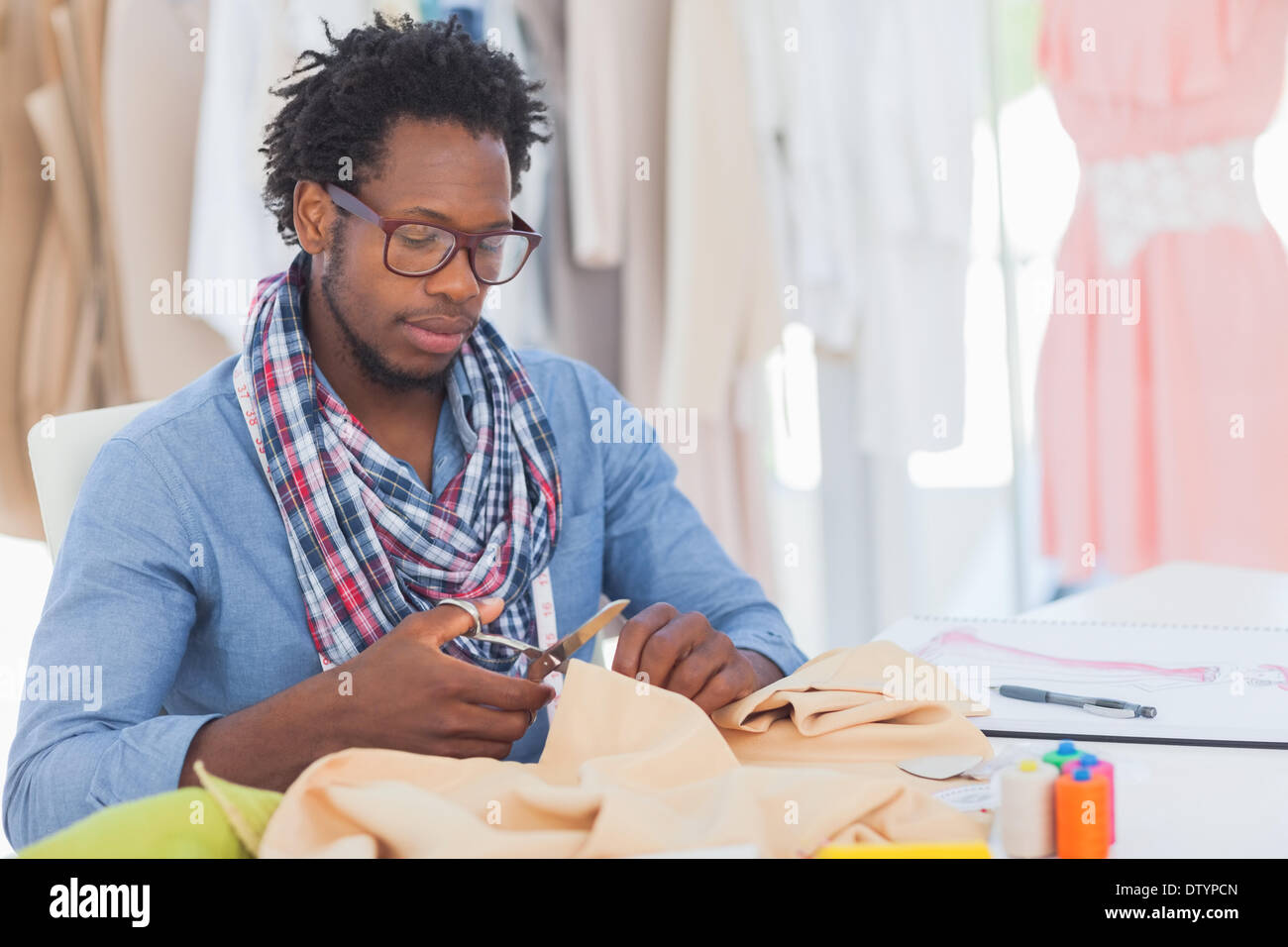 Serious fashion designer cutting textile Stock Photo - Alamy