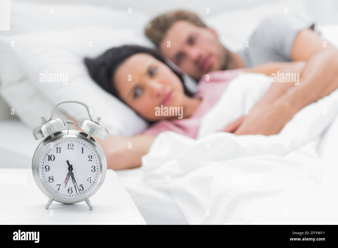 Tired couple looking at the alarm clock Stock Photo - Alamy